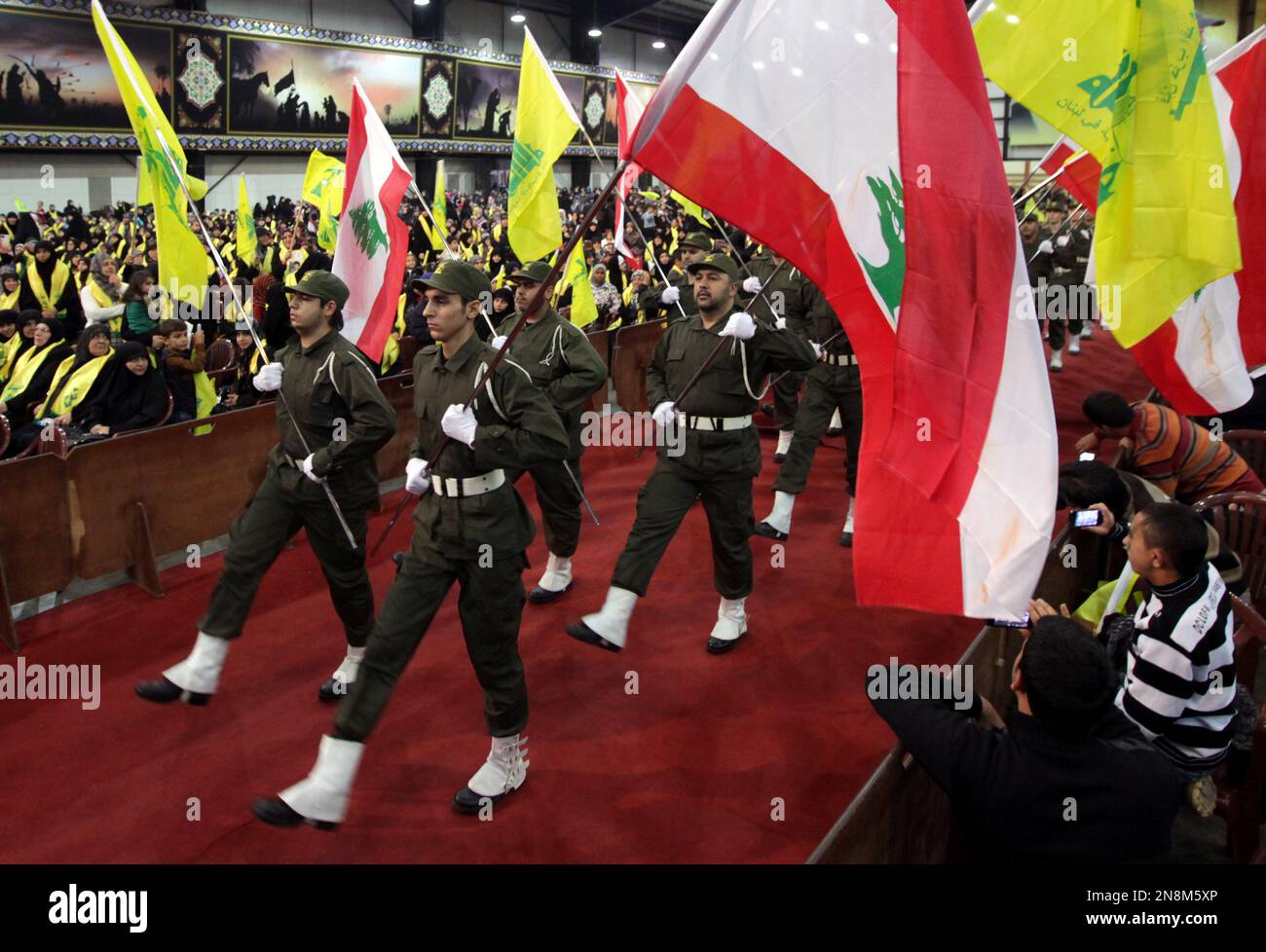 Hezbollah members, hold Hezbollah and Lebanese flags as they march ...