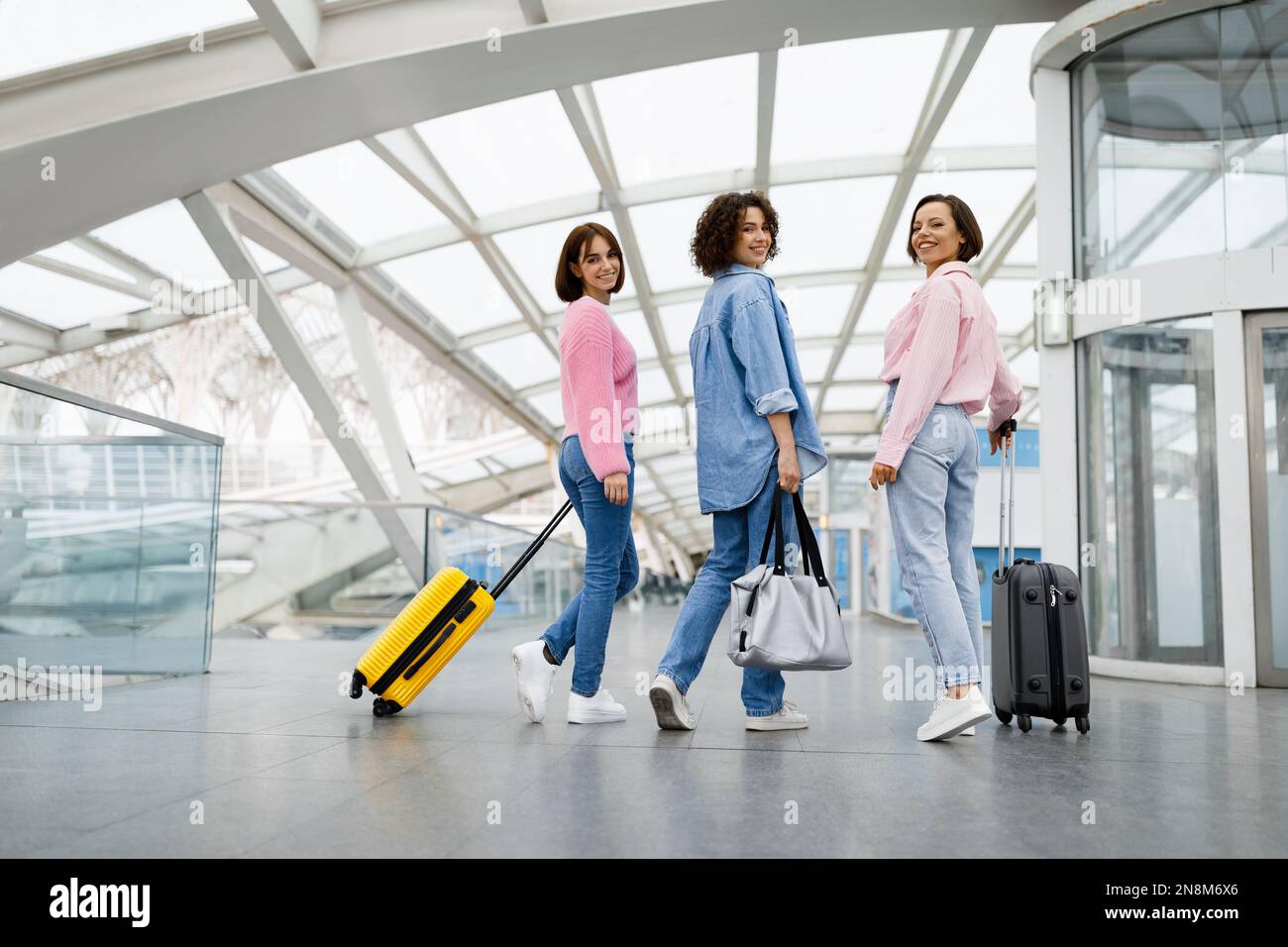 Three Beautiful Women Walking With Luggage At Airport And Turning At ...
