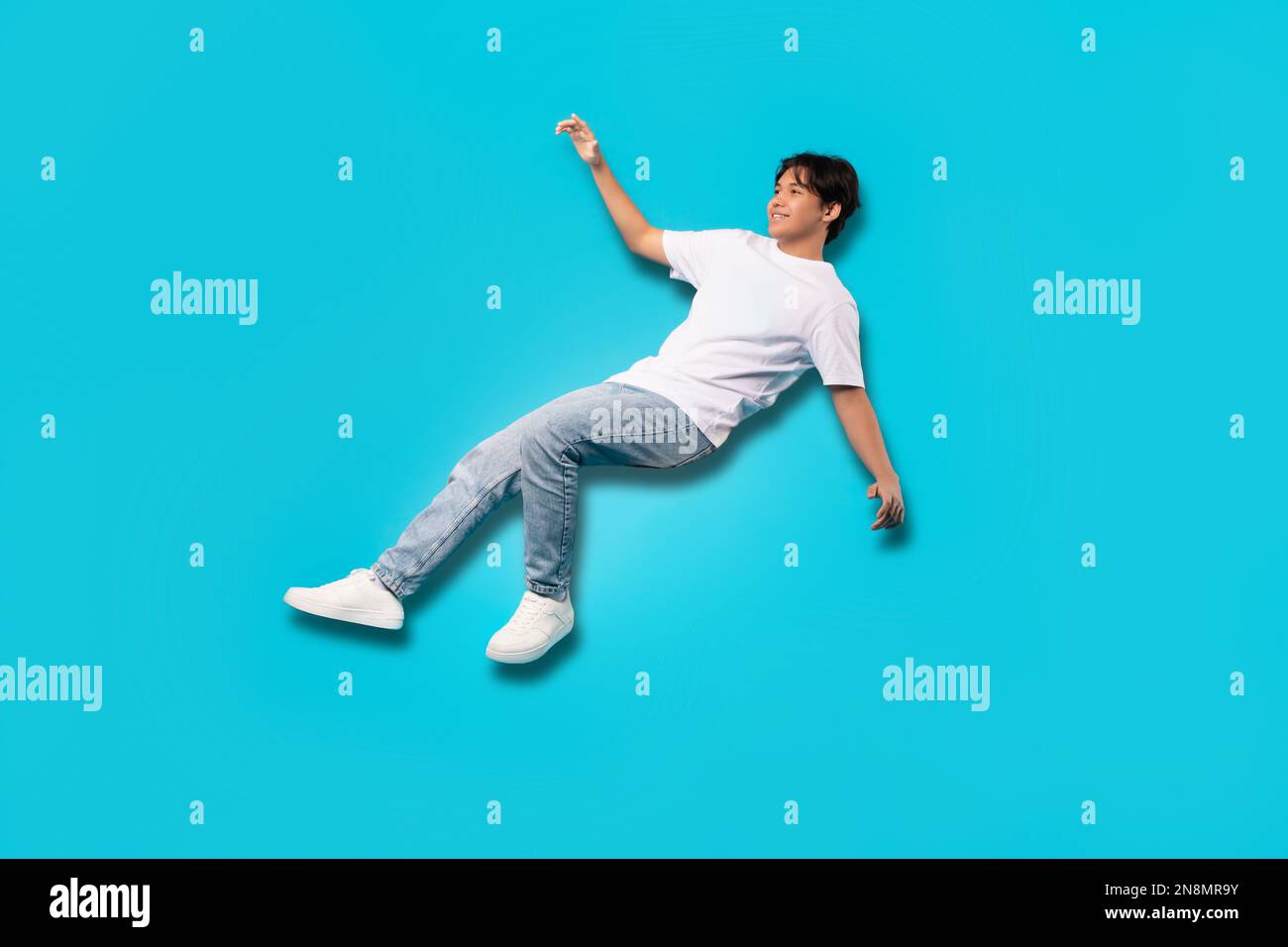 Asian Teenager Boy Falling In Mid Air Over Blue Background Stock Photo ...