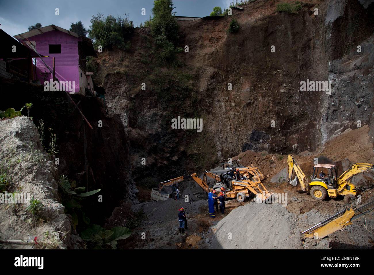 Residents and rescue workers use heavy equipment to look for people ...