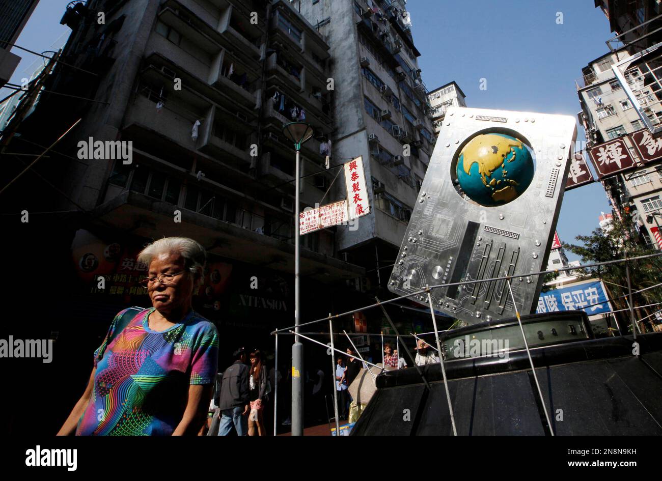 A woman walks past a monument called Digital Hub Logo at Sham Shui Po ...