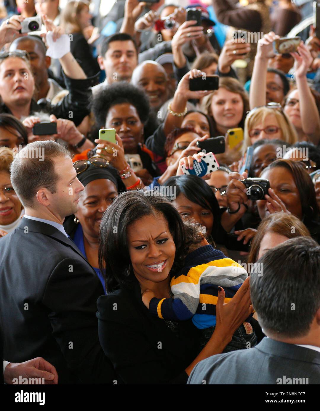 First lady Michelle Obama holds a child as she greets supporters ...
