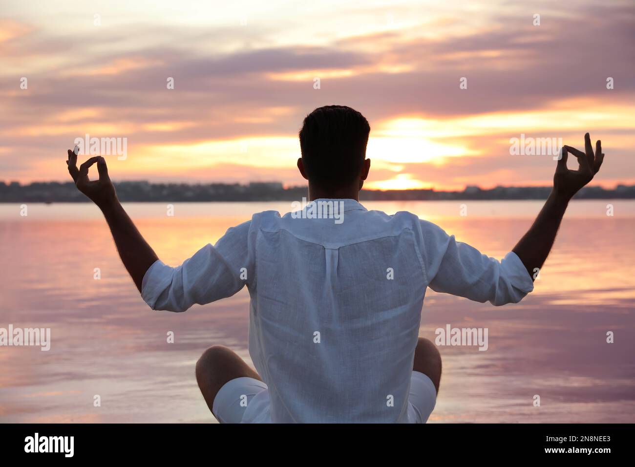 Man near river at sunset, back view. Nature healing power Stock Photo ...