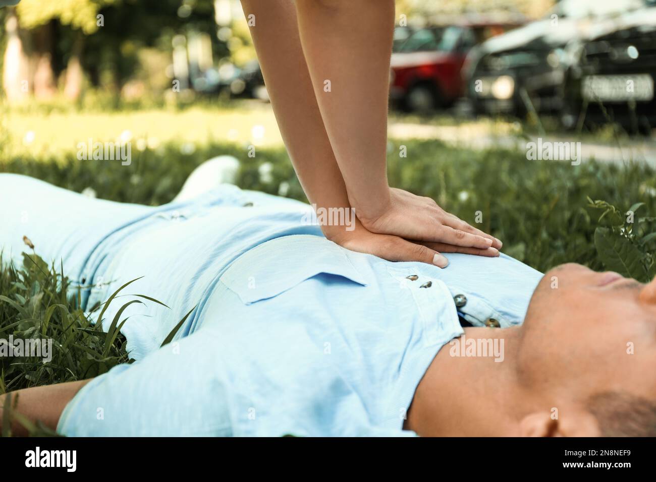 Young woman performing CPR on unconscious man outdoors, closeup. First ...