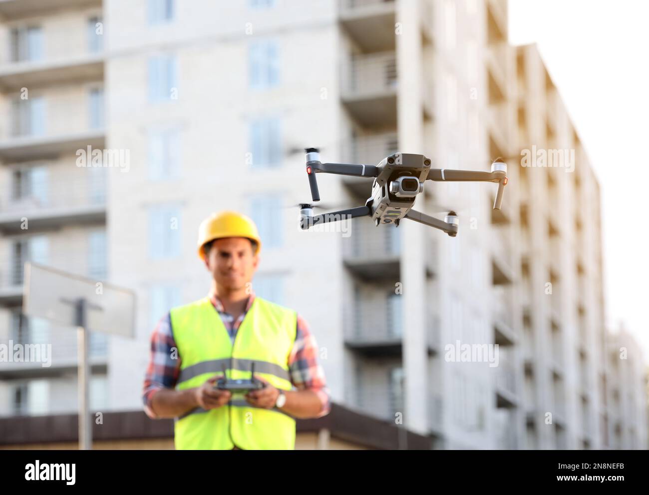 Builder operating drone with remote control at construction site ...