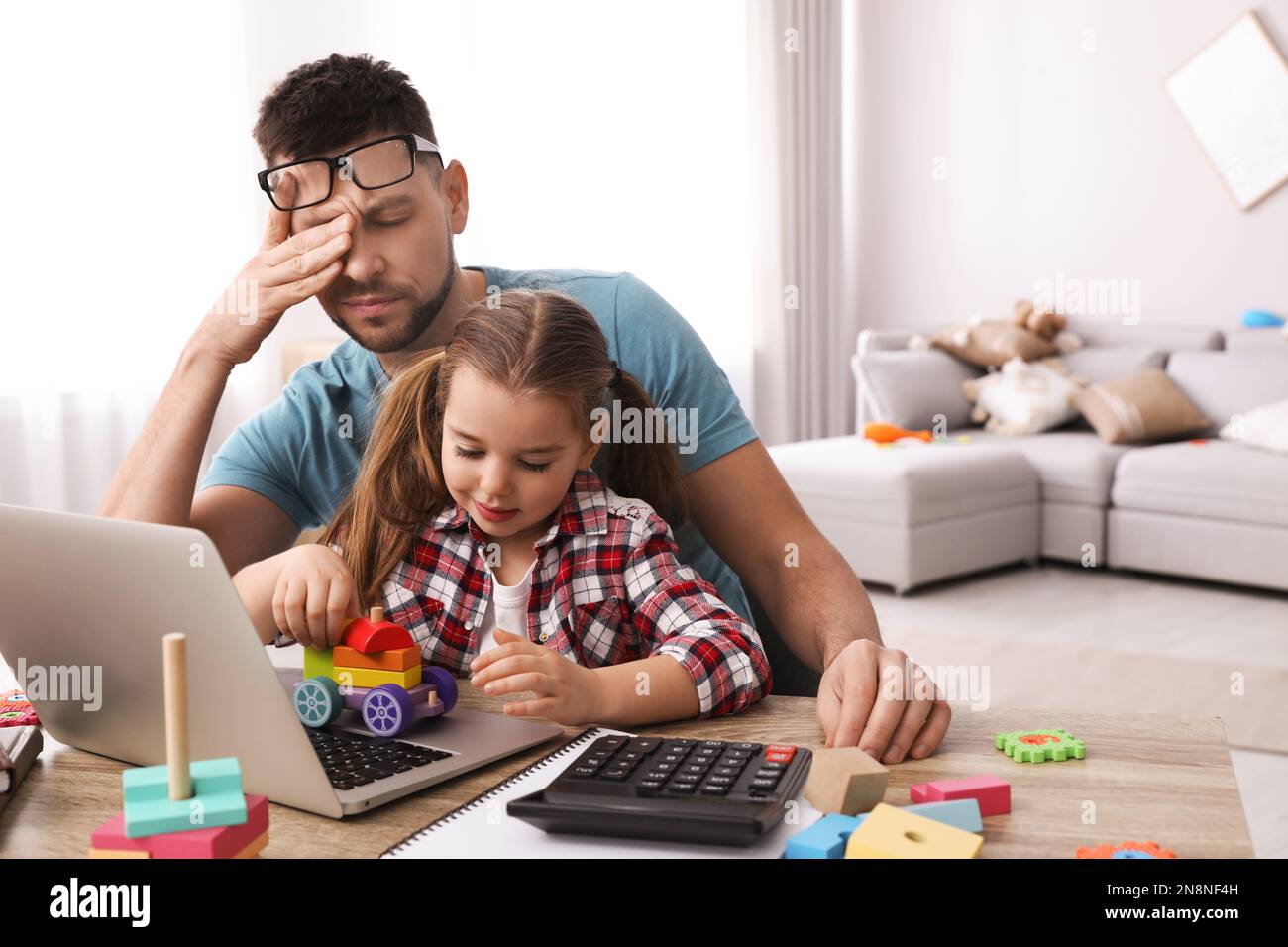 Cute child disturbing stressed man in living room. Working from home ...