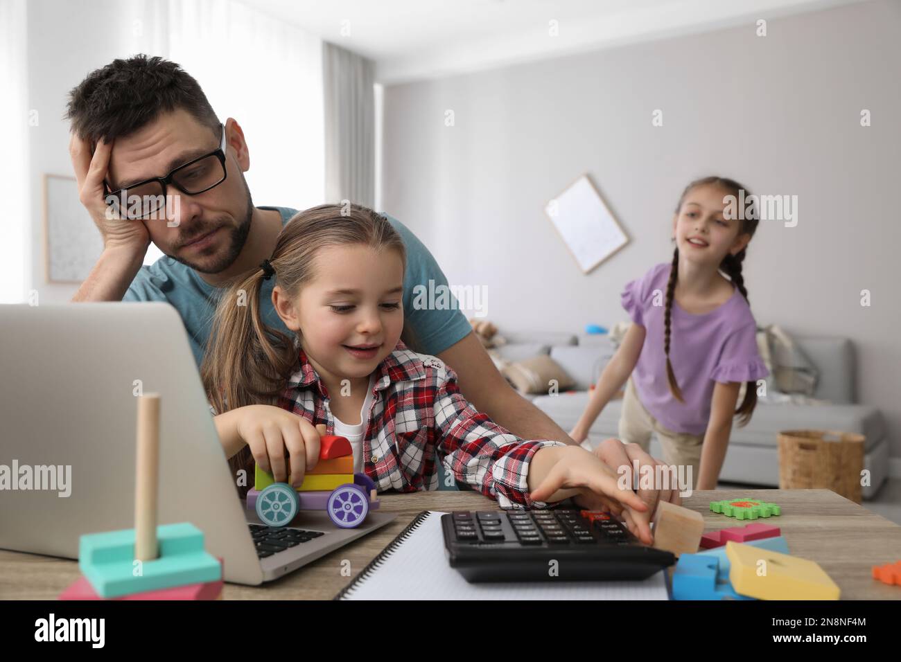 Children disturbing stressed man in living room. Working from home ...