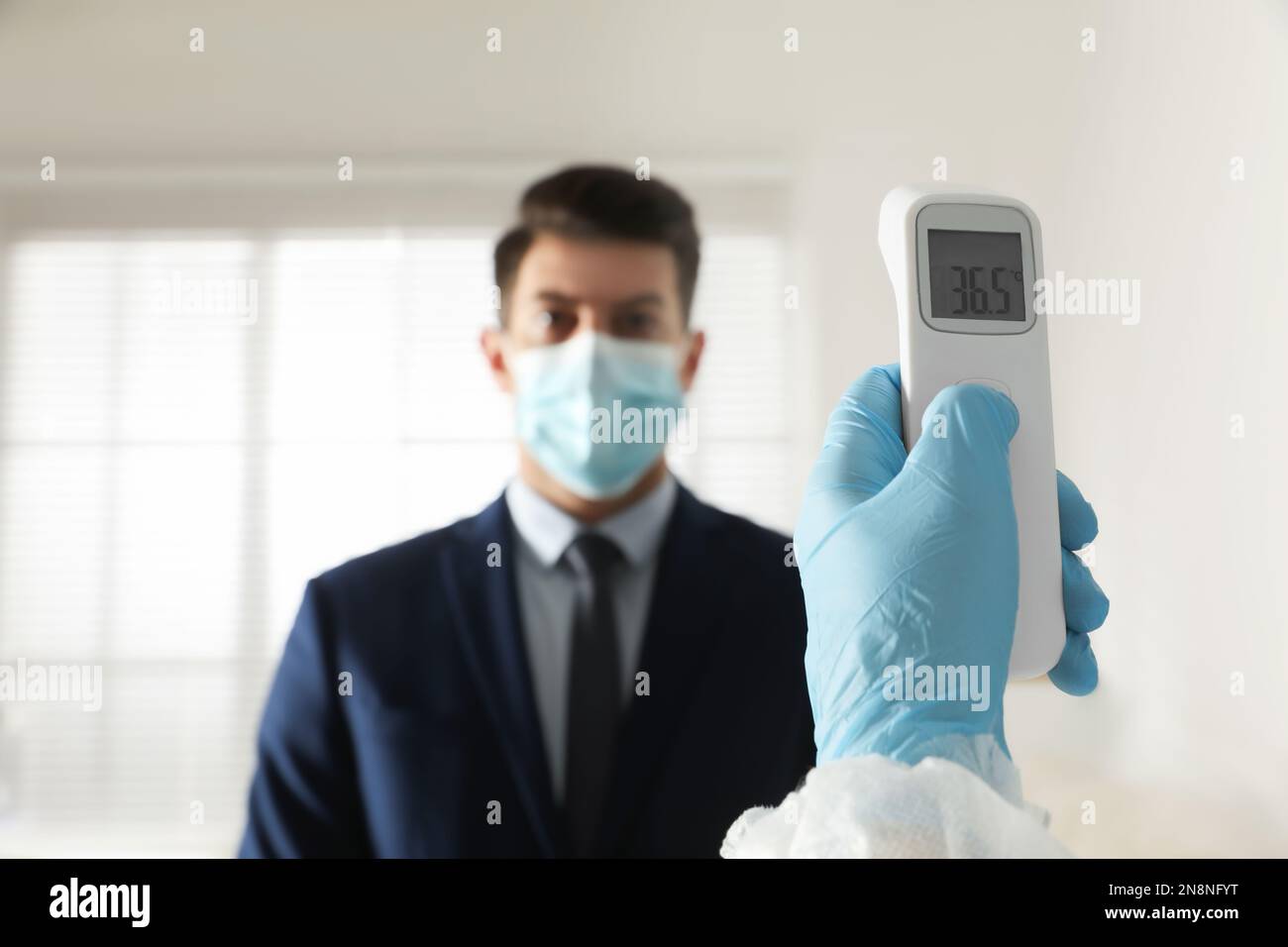 Doctor measuring man's temperature in office closeup. Prevent spreading ...