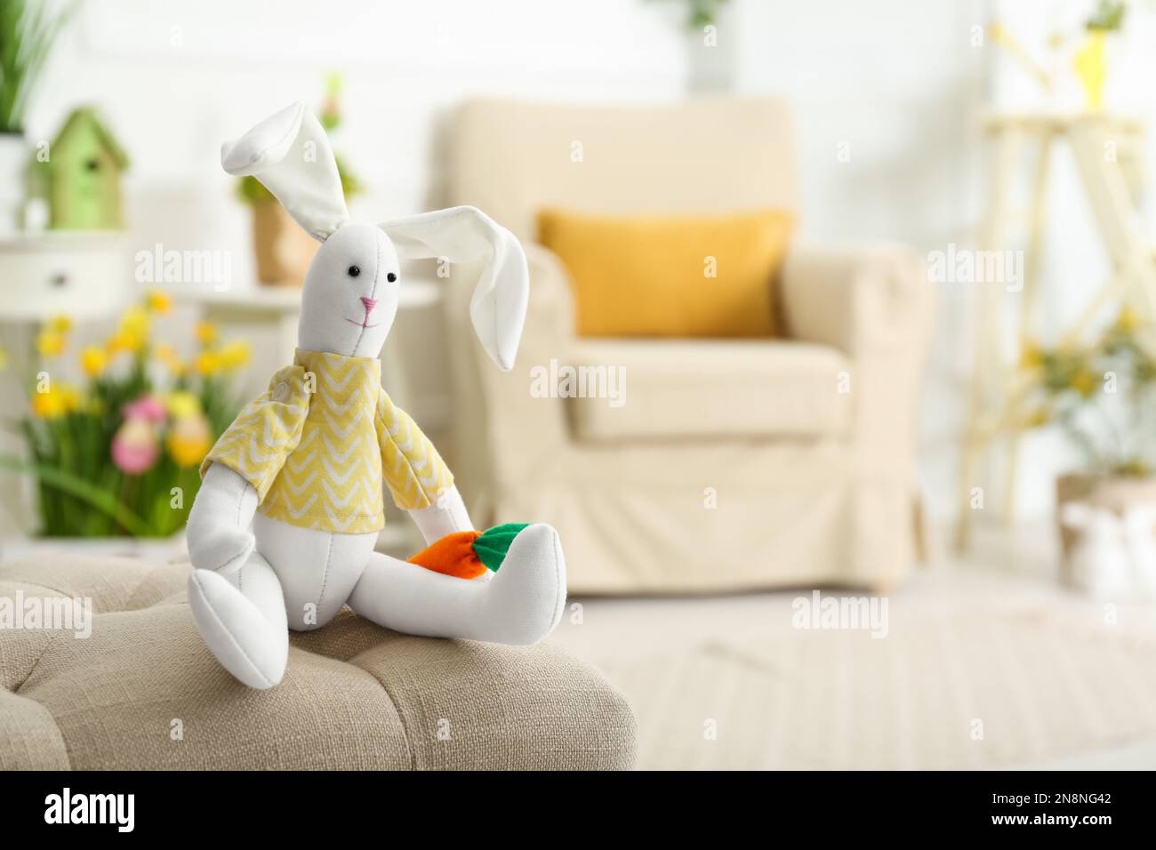 Cute toy rabbit on bench indoors. Easter photo zone Stock Photo - Alamy