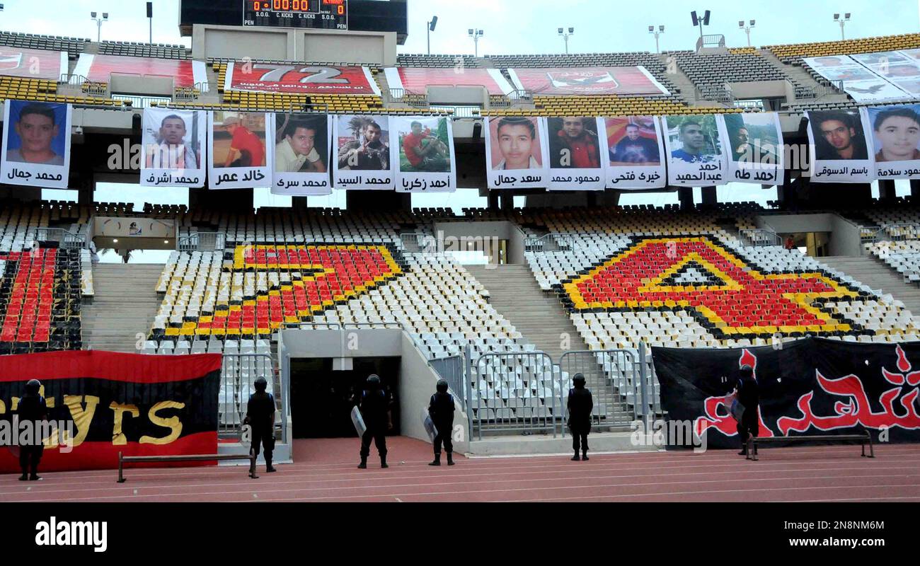 Egyptian riot police stand guard beneath portraits of soccer fans who ...