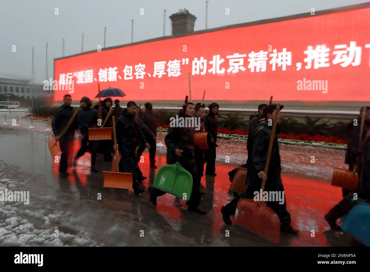 Chinese paramilitary police march off with shovels near a sign which ...