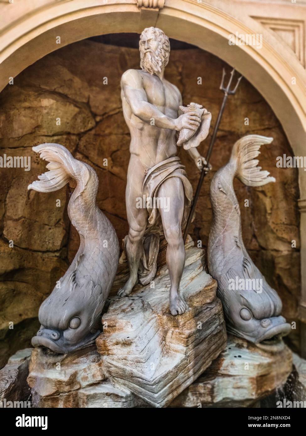 A vertical shot of a sculpture of Poseidon with dolphins in Epcot ...