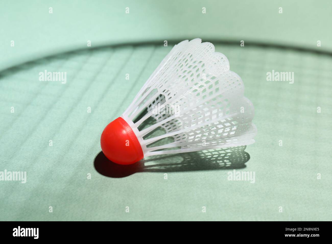 Plastic shuttlecock and shadow of racquet on light background, closeup ...