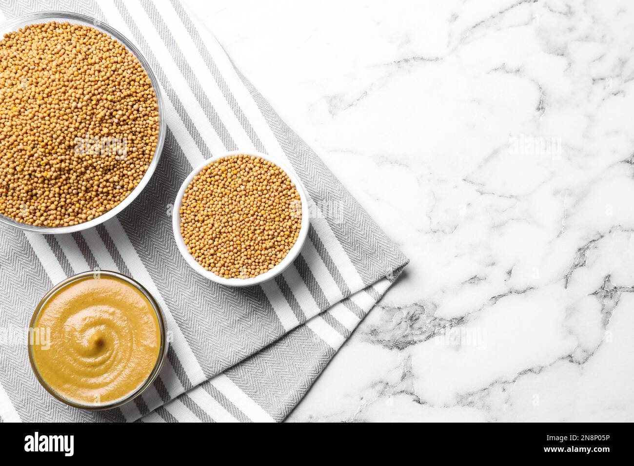 Flat lay composition with mustard seeds on white marble table, space ...