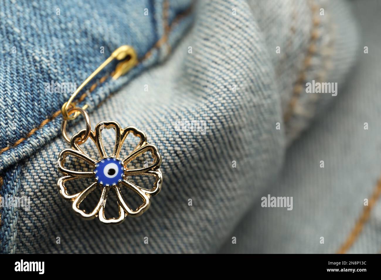 Evil eye safety pin on denim clothing, closeup Stock Photo - Alamy