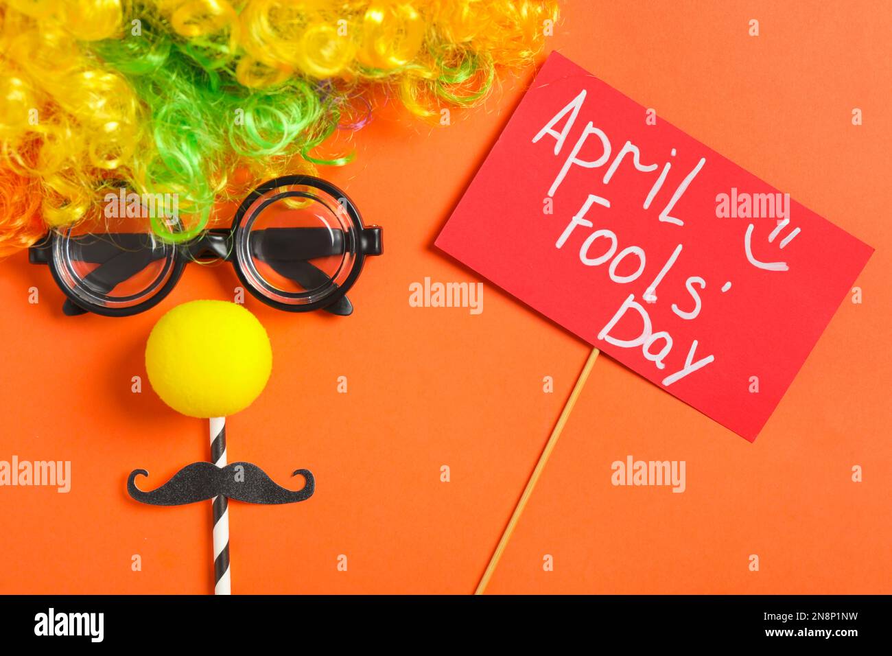 Funny face made of clown's accessories and sign with phrase April Fools ...