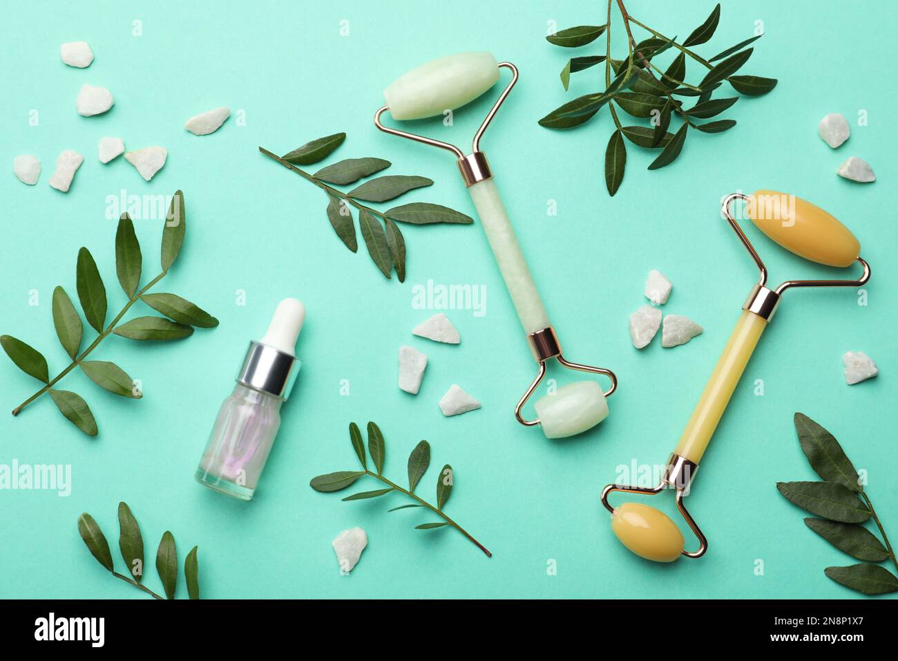 Natural face rollers, cosmetic product and leaves on turquoise ...