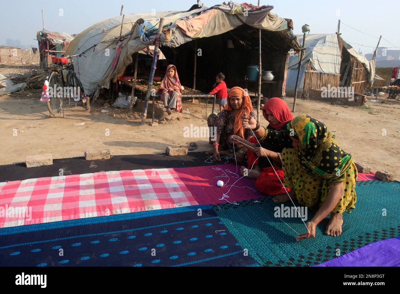 Pakistani women prepare a curtain for their make-shift tent as winter ...