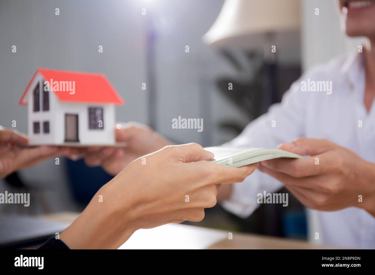 Closeup hand of young realtor woman giving house model to hands ...