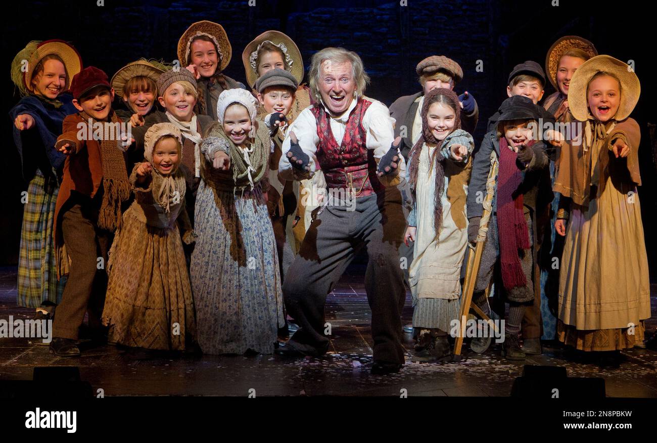 Tommy Steele as Ebenezer Scrooge, centre, performs a scene on stage as ...