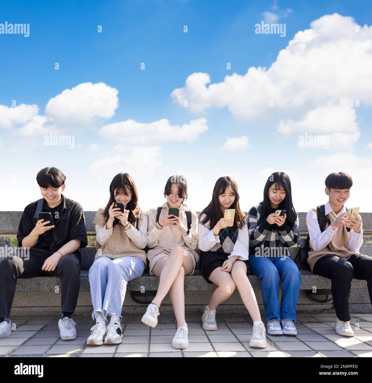 Happy young group using the mobile phones with cloud background Stock ...