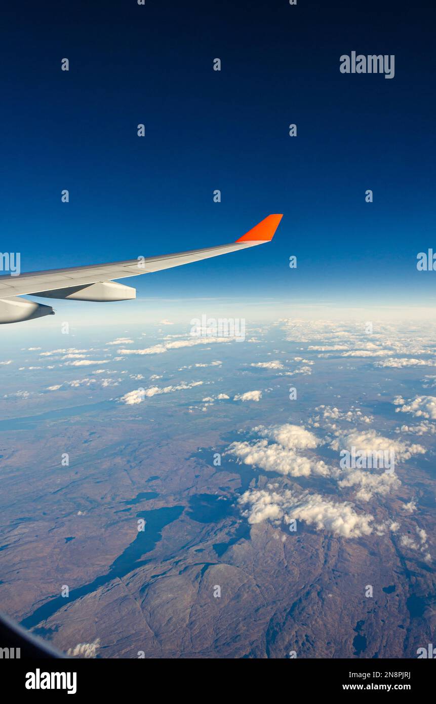 Plane wing, white clouds, blue sky and ground Stock Photo - Alamy