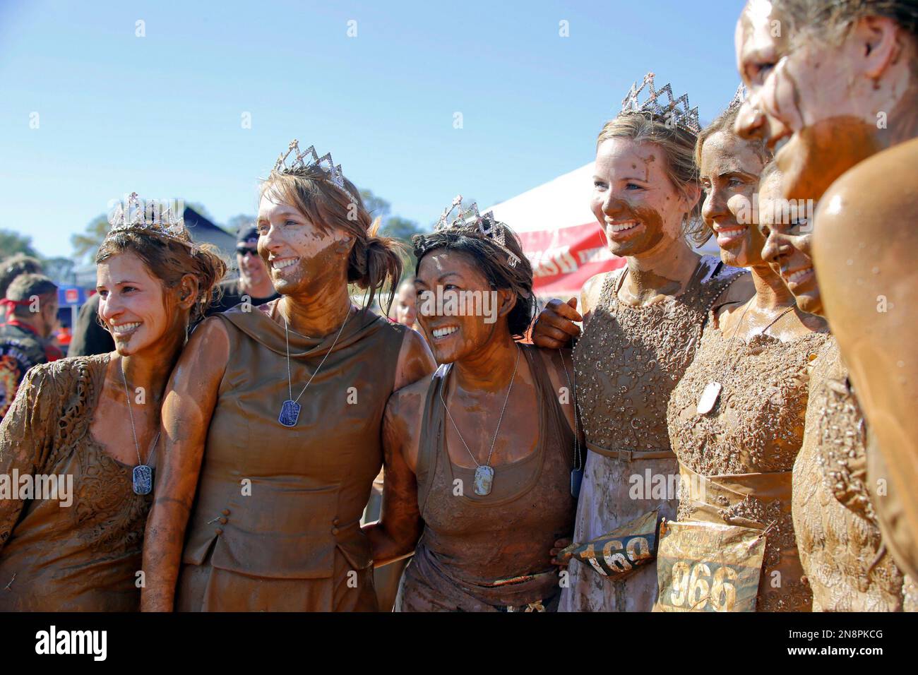 A group of female competitors dressed in muddy wedding gowns pose for a ...