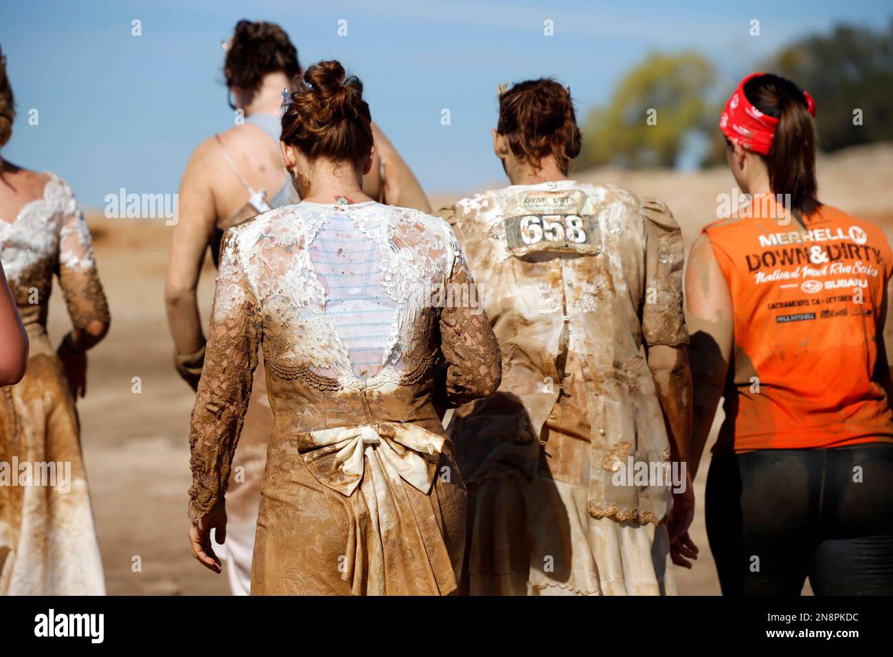 Competitors dressed in muddy wedding gowns head to the finish line of ...