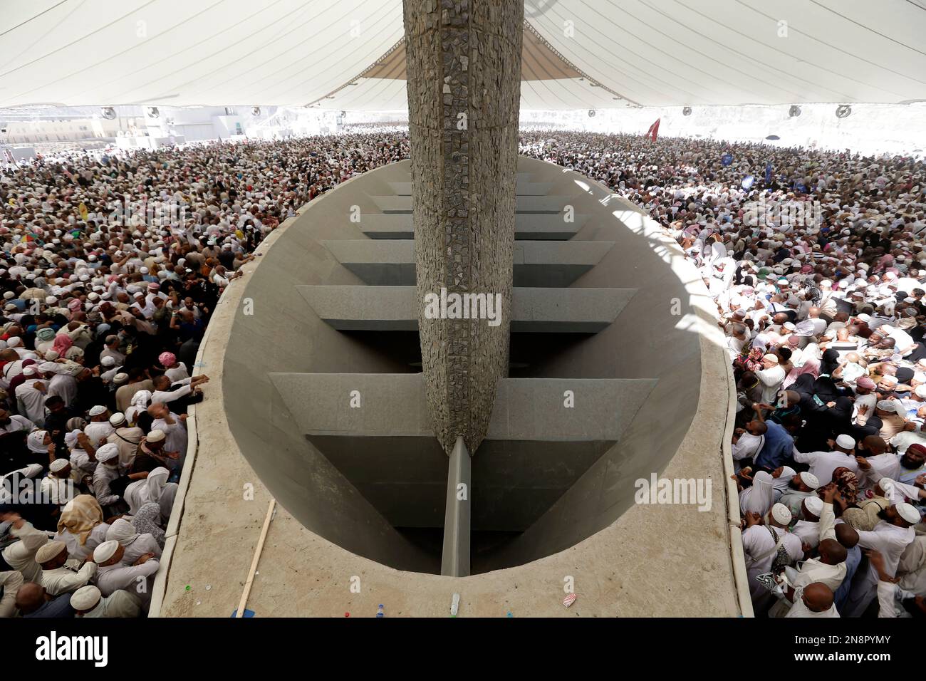 Muslim pilgrims cast stones at a pillar, symbolizing the stoning of ...