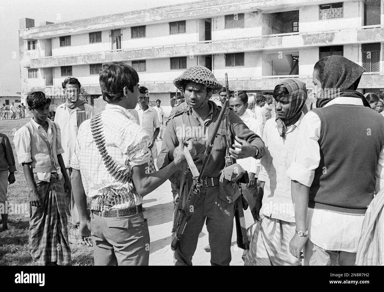 An Indian soldier disarms Mukti Bahini irregulars at the edge of the ...