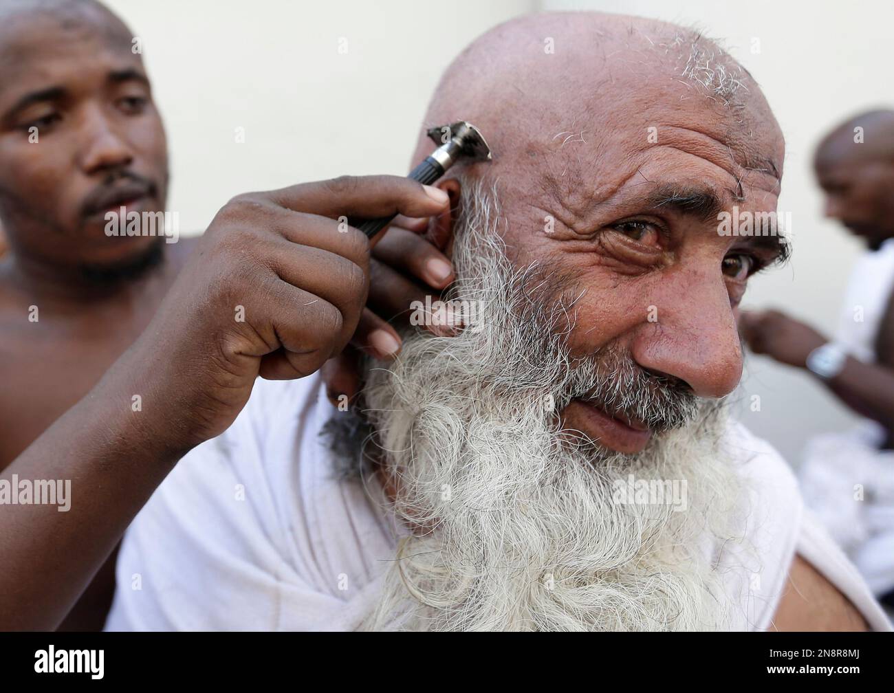 A Muslim pilgrim has his head ritually shaved after he cast stones at a ...