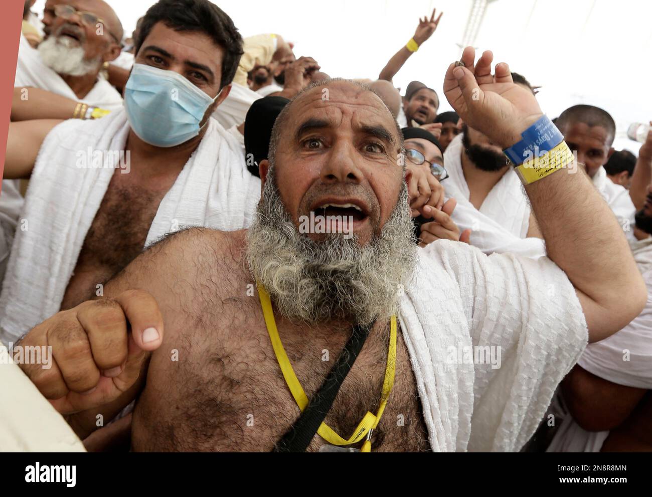 Muslim pilgrims cast stones at a pillar, symbolizing the stoning of ...