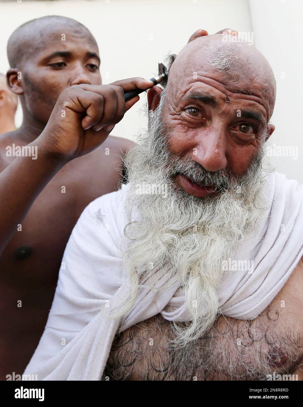 A Muslim pilgrim has his head ritually shaved after he cast stones at a ...
