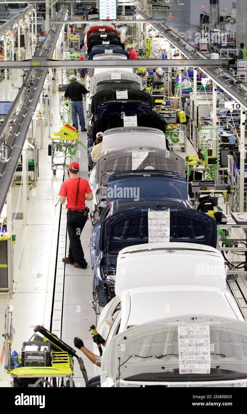 Toyota team members work Corollas as they roll down the assembly line ...