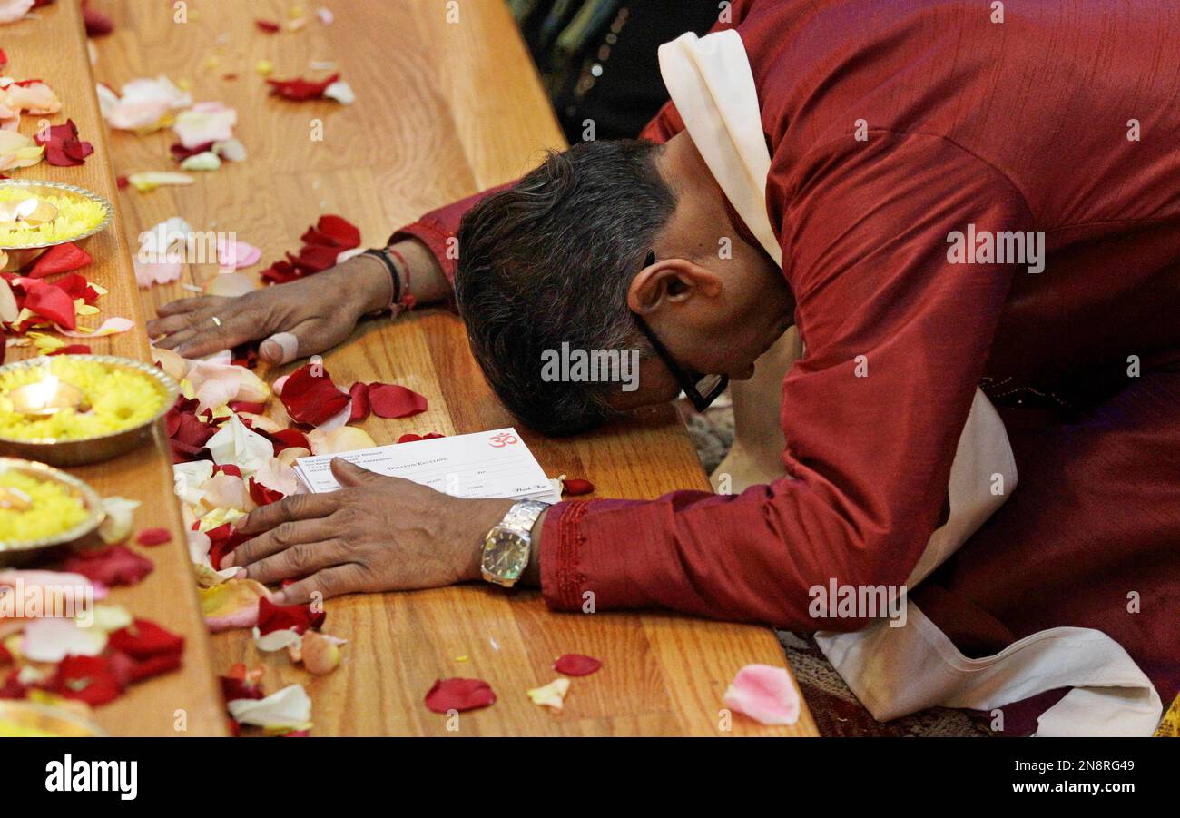 A man bows before the rose-petal strewn altar adorned with Hindu ...