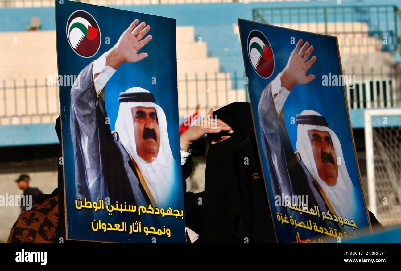 A Palestinian Hamas supporter holds posters of the Emir of Qatar Sheikh ...