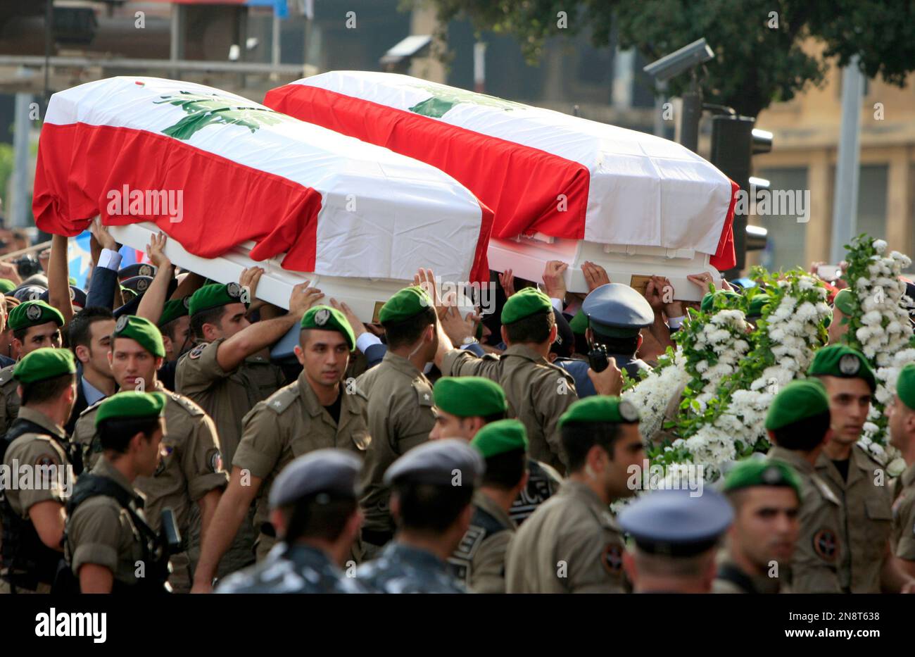 A Lebanese honor guard carries coffins wrapped with Lebanese flags of ...