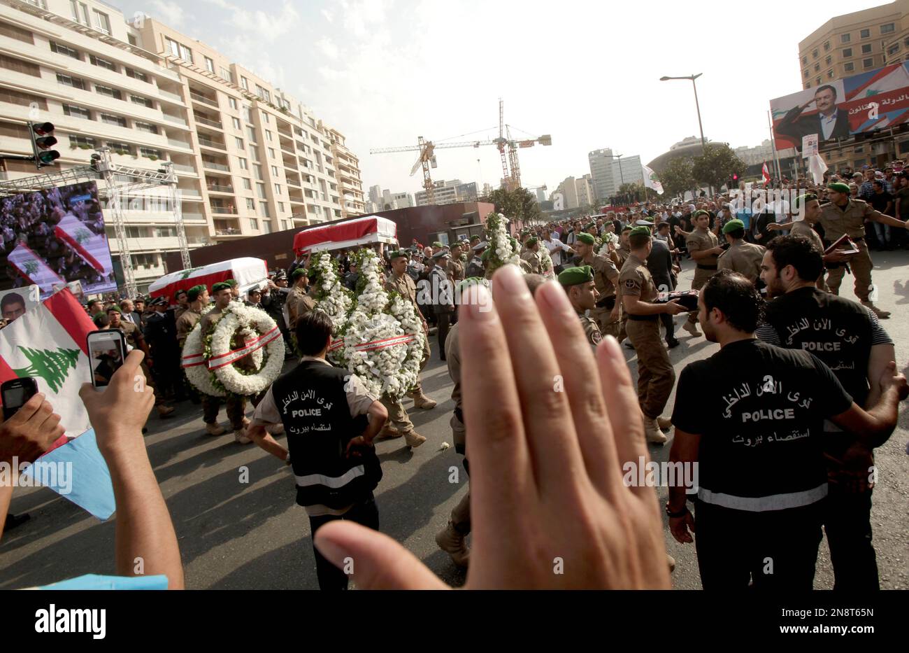 Mourners wave and take pictures as a Lebanese honor guard carries ...