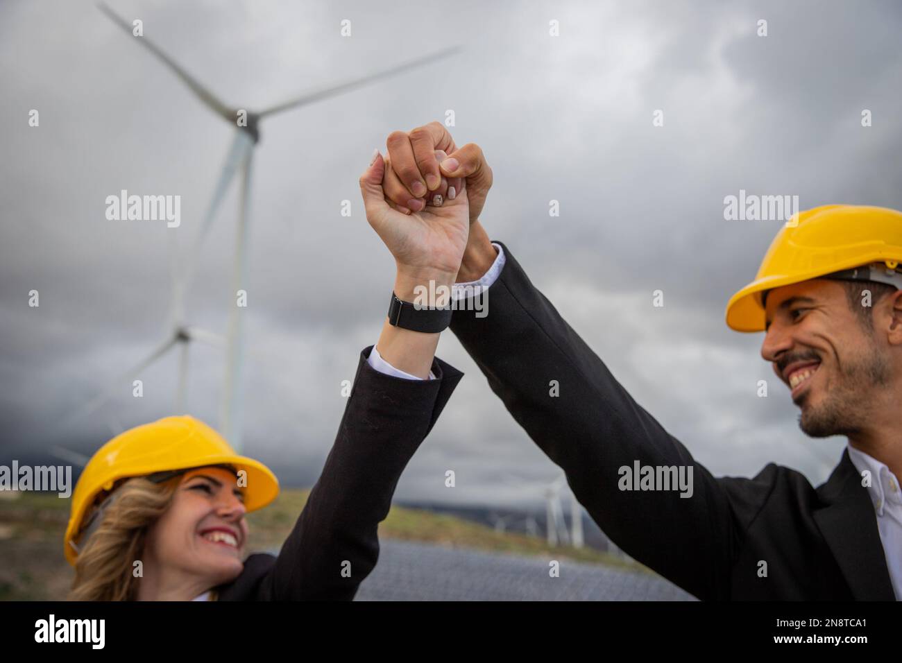 Two engineers celebrate a business success by joining hands in the sky ...