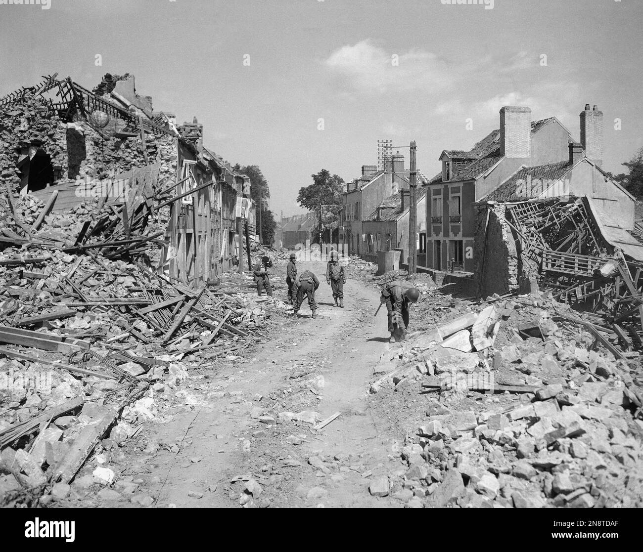 American soldiers patrol a shell-shattered street in St. Sauveur ...