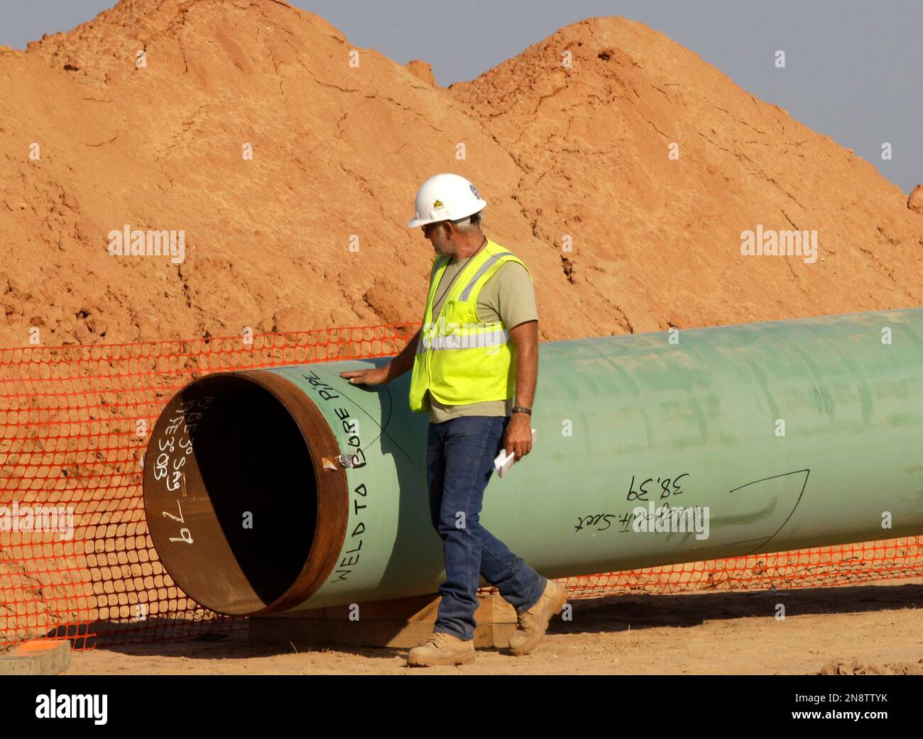 A pipeline worker walks the length of a pipe as work continues Thursday ...