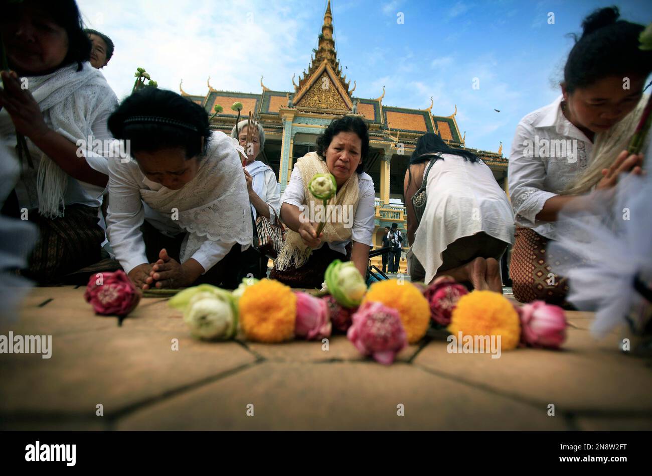 Elderly women lay flower offerings and chant prayers at the Royal ...