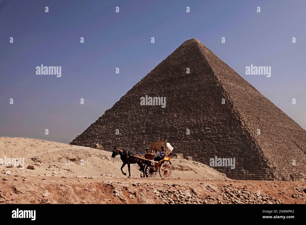 Egyptians ride a carriage past the pyramid of Khufu, background, near ...
