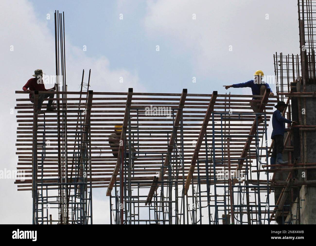 Workers balance on scaffolding while constructing a building in Bangkok ...