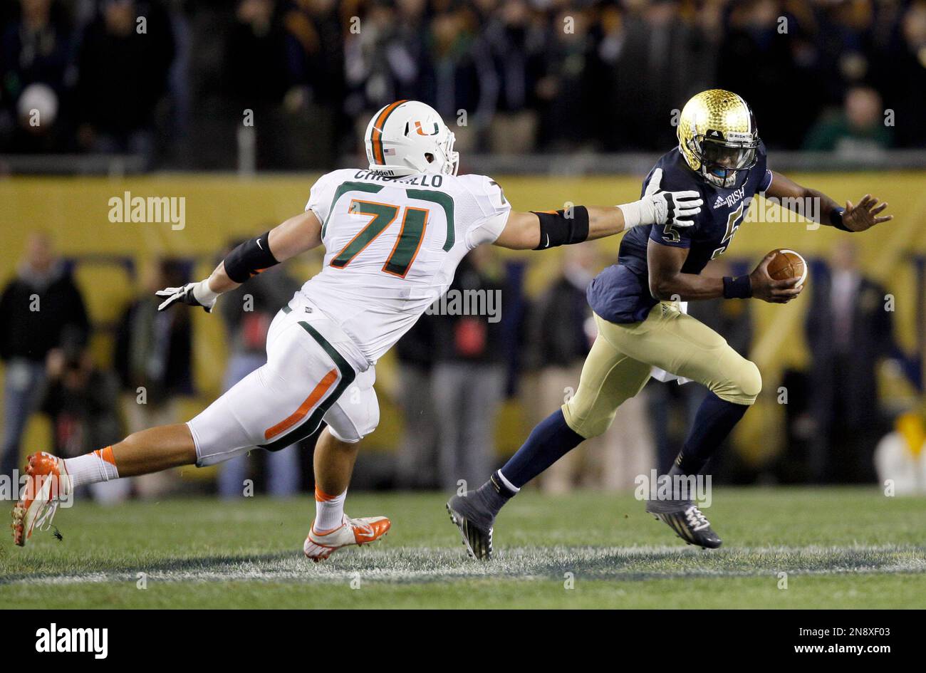 Notre Dame quarterback Everett Golson, right, eludes the grasp of Miami ...