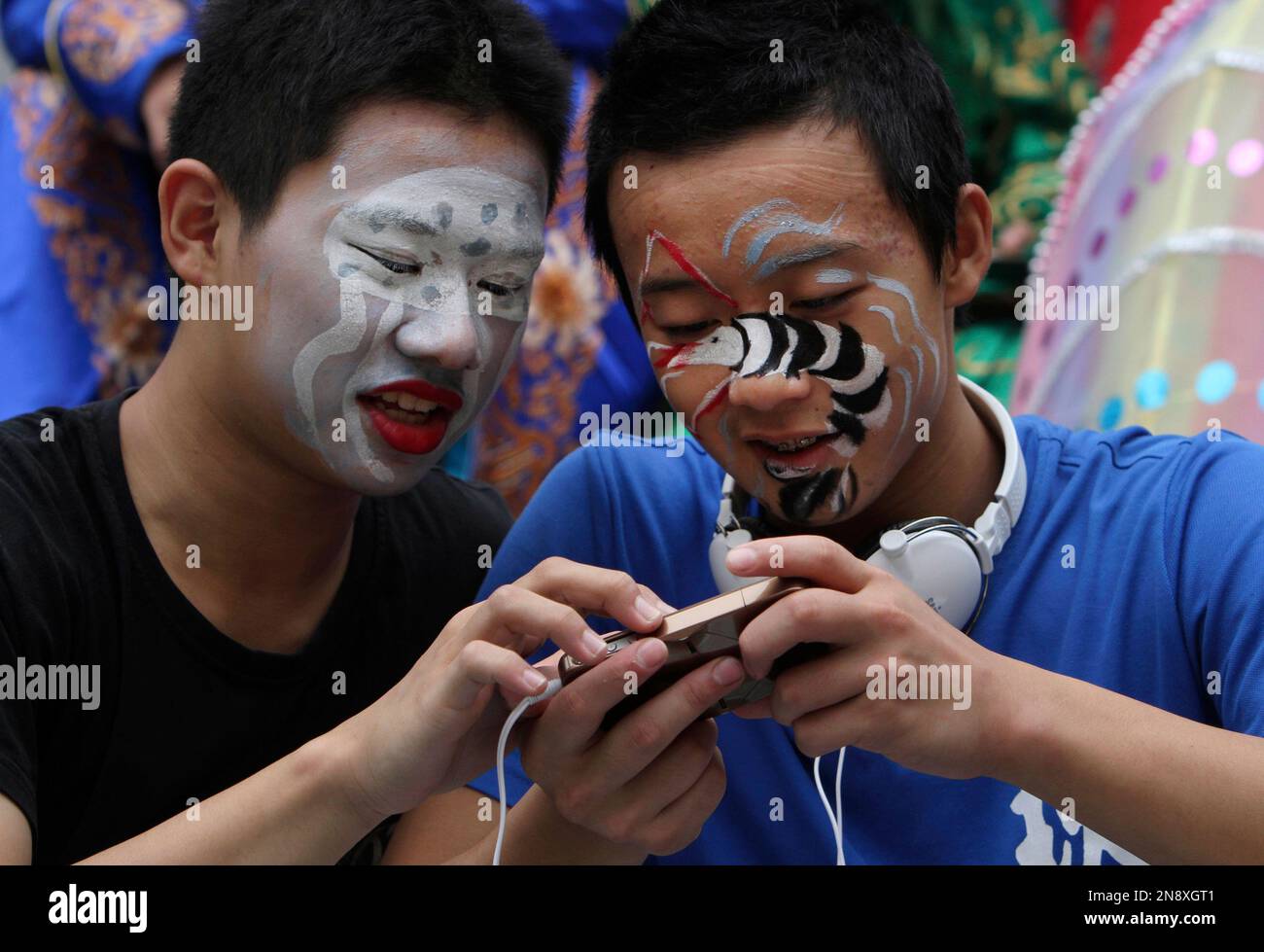 Two Taiwanese performers play with a smartphone during a break at the ...