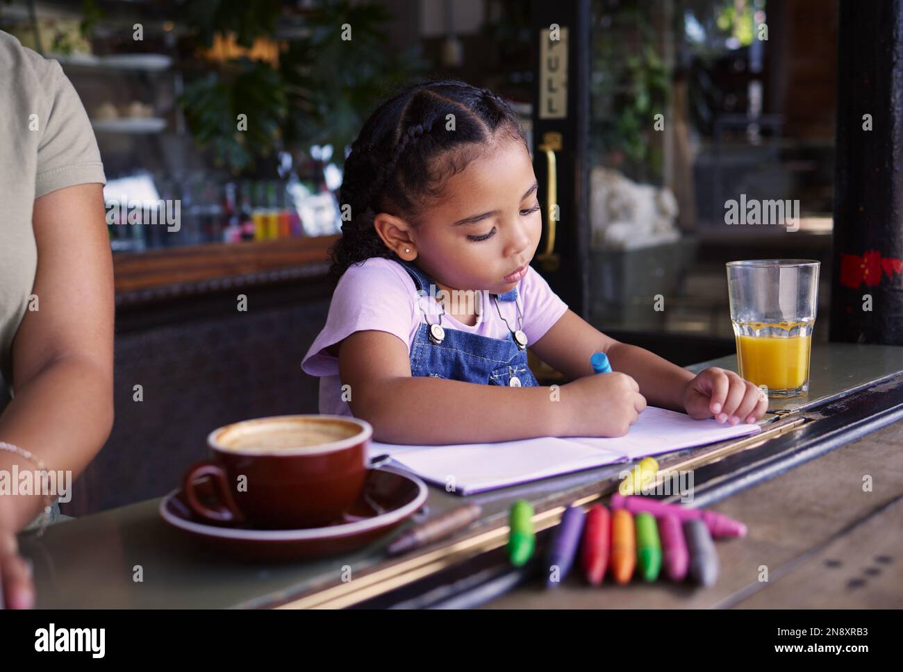 Girl child color in book at cafe, creative and drawing with crayons, family day to relax with ...