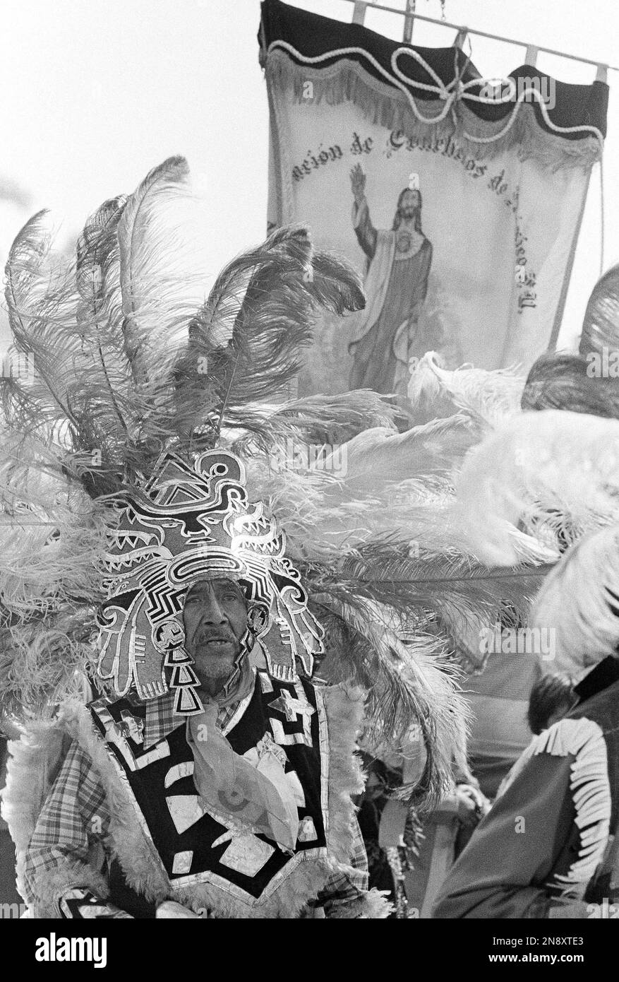 A dancer dressed in Mexican Indian costume dances in front of a tilma ...