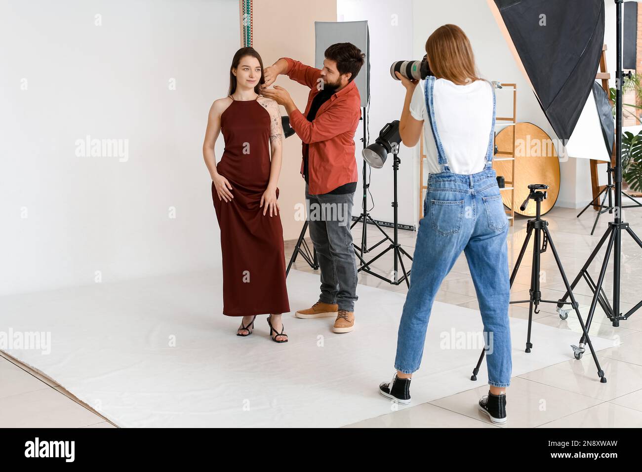 Female photographer and her assistant working with beautiful model in ...