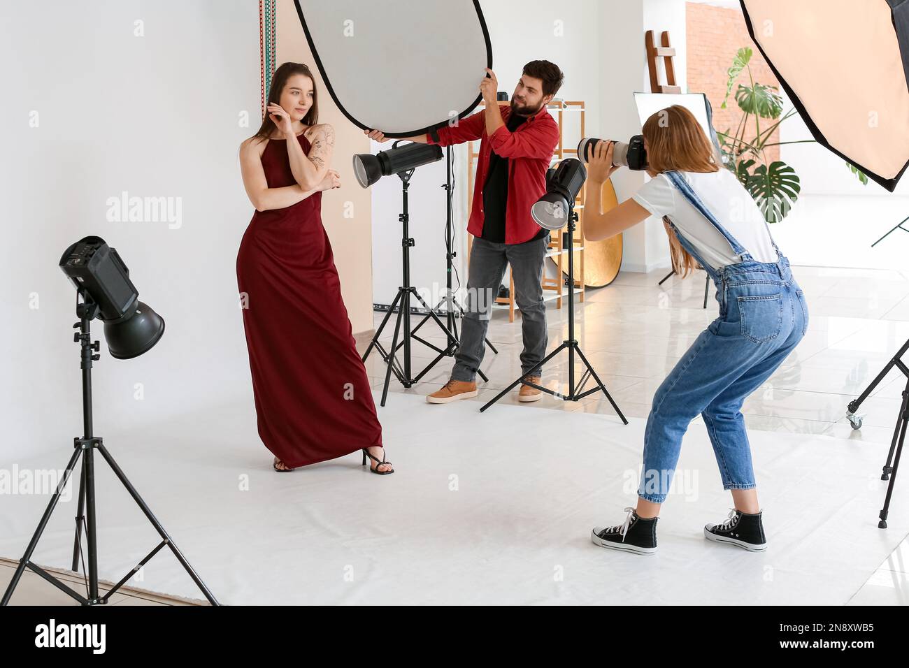 Female photographer and her assistant working with beautiful model in ...